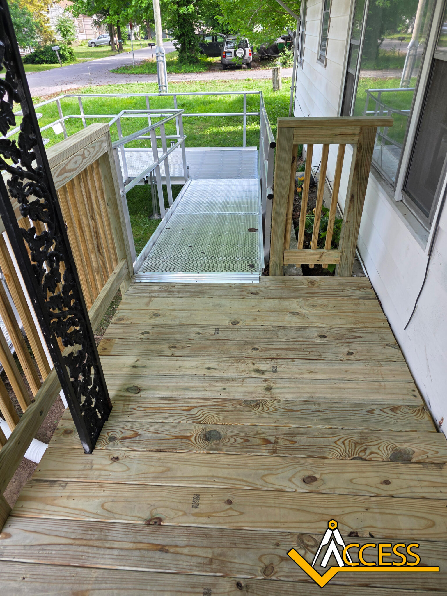 View from a wooden porch looking down at an aluminum wheelchair ramp ...
