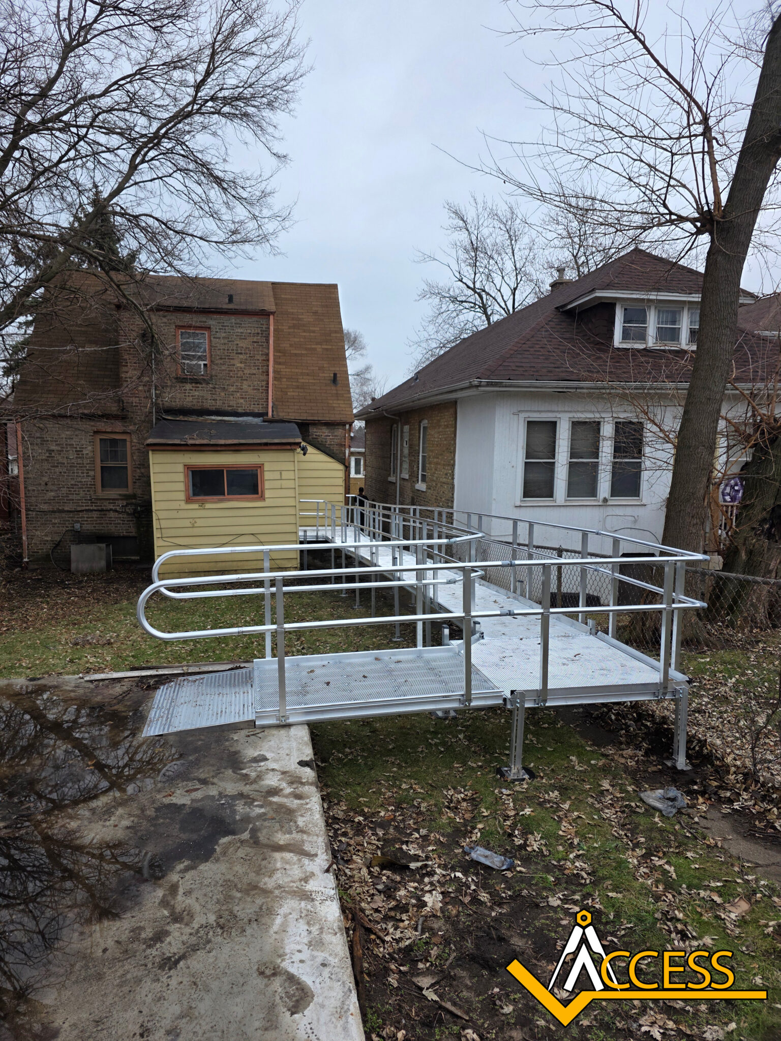 A metal wheelchair ramp leads from a paved walkway to the back entrance ...
