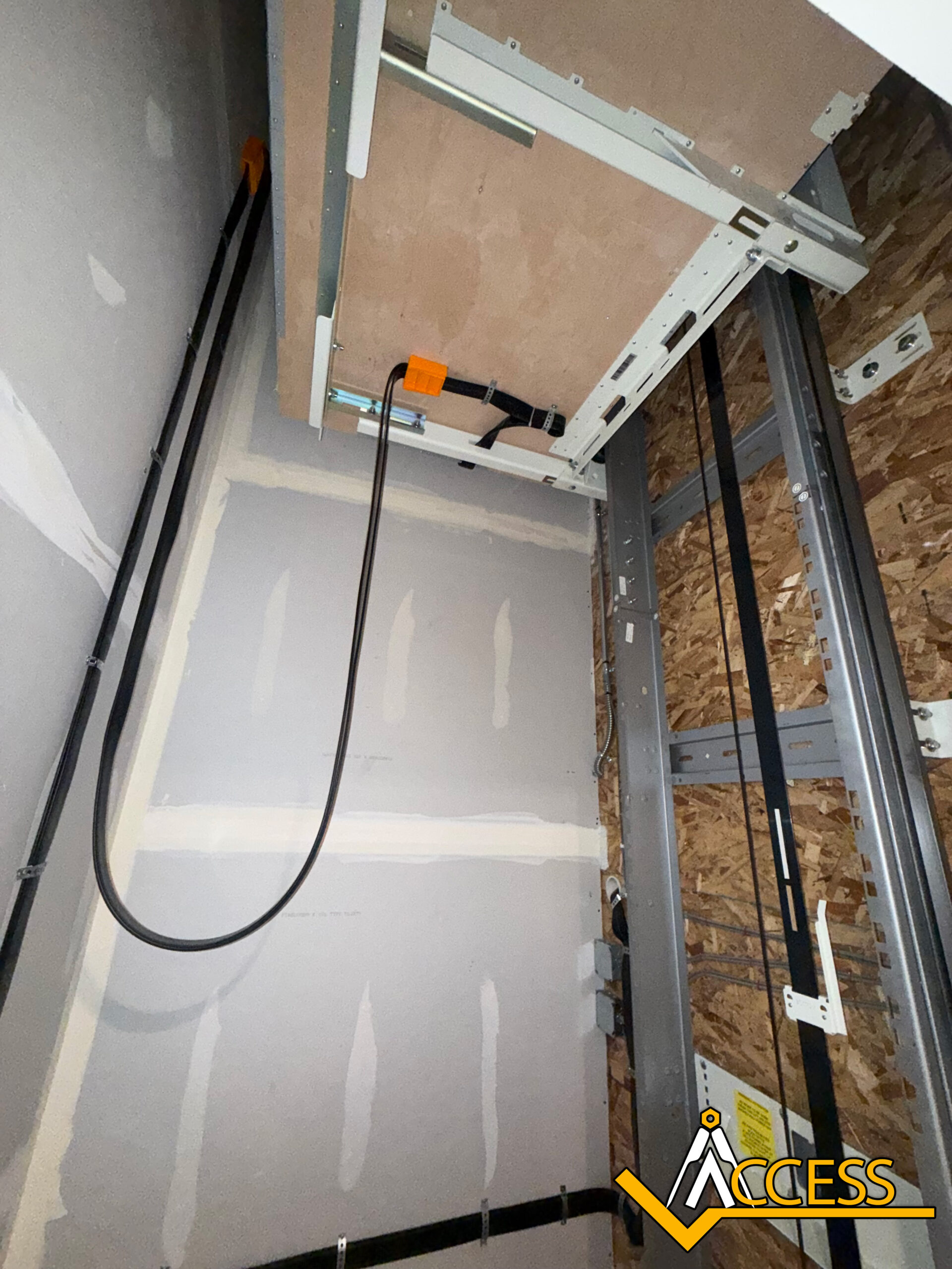 View from the bottom of an elevator shaft showing cables, rails, and a ...