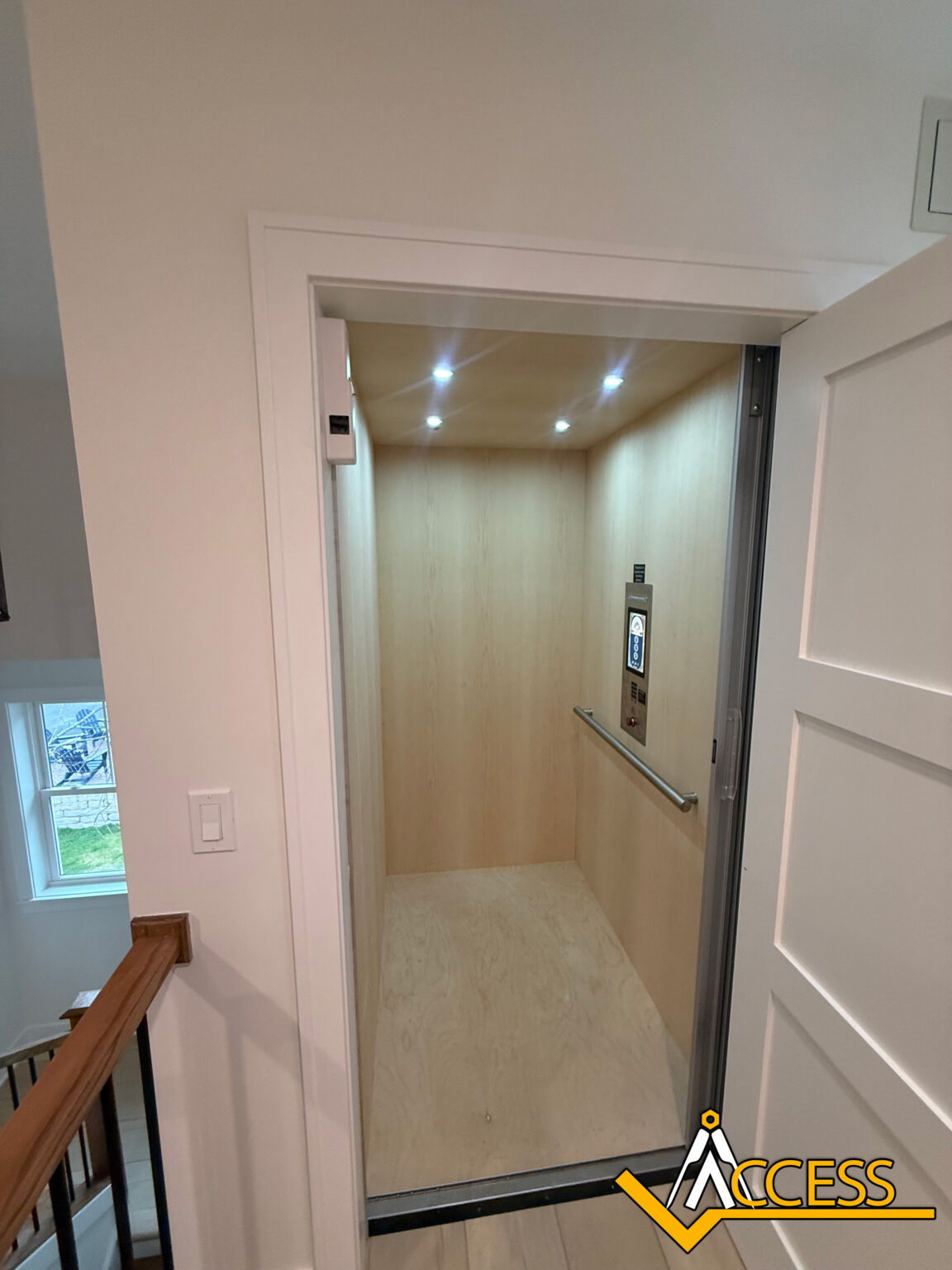A small residential elevator with wood-paneled walls and floor, metal ...