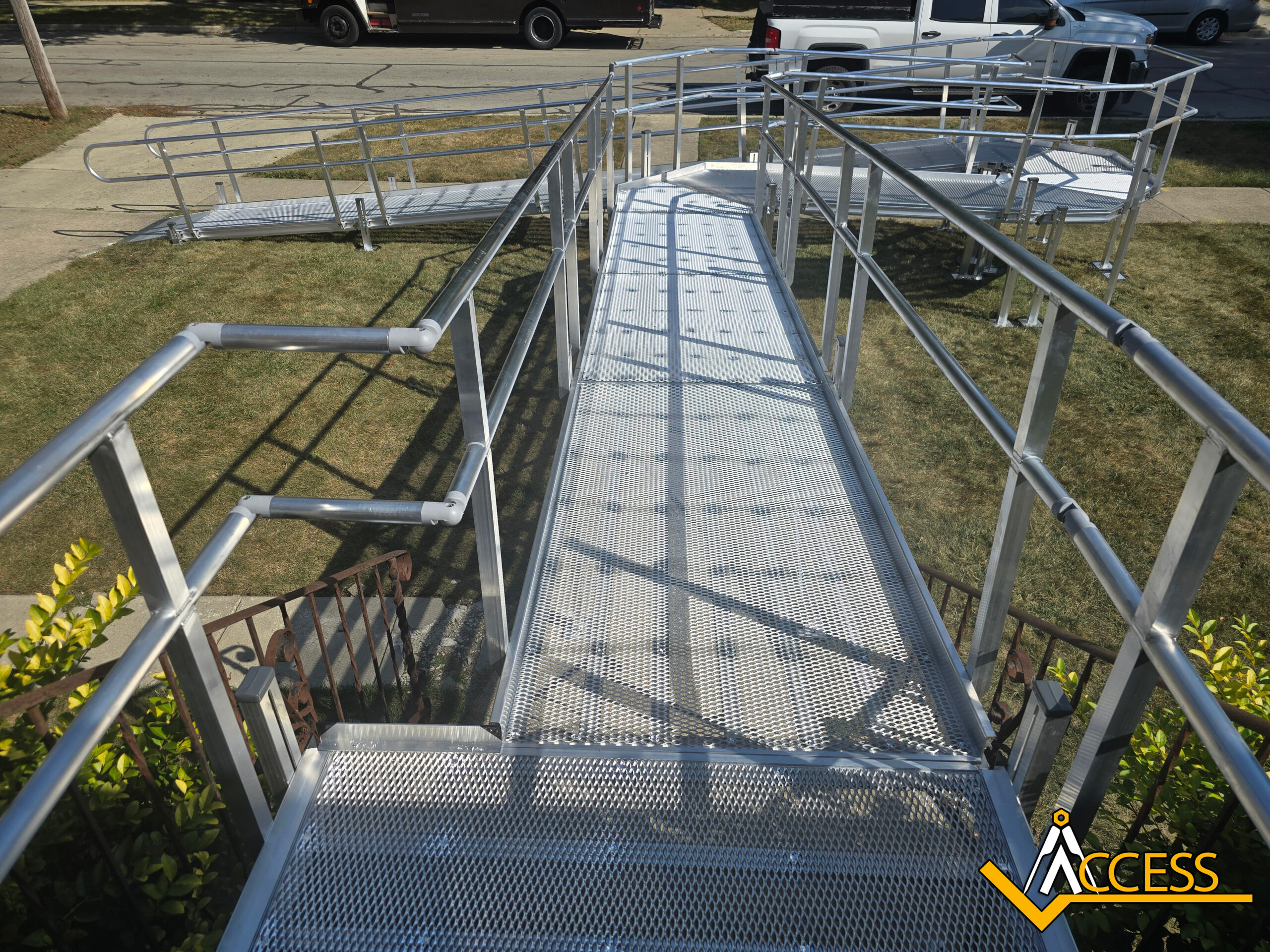 A metal wheelchair ramp with railings extends from a doorway across a ...