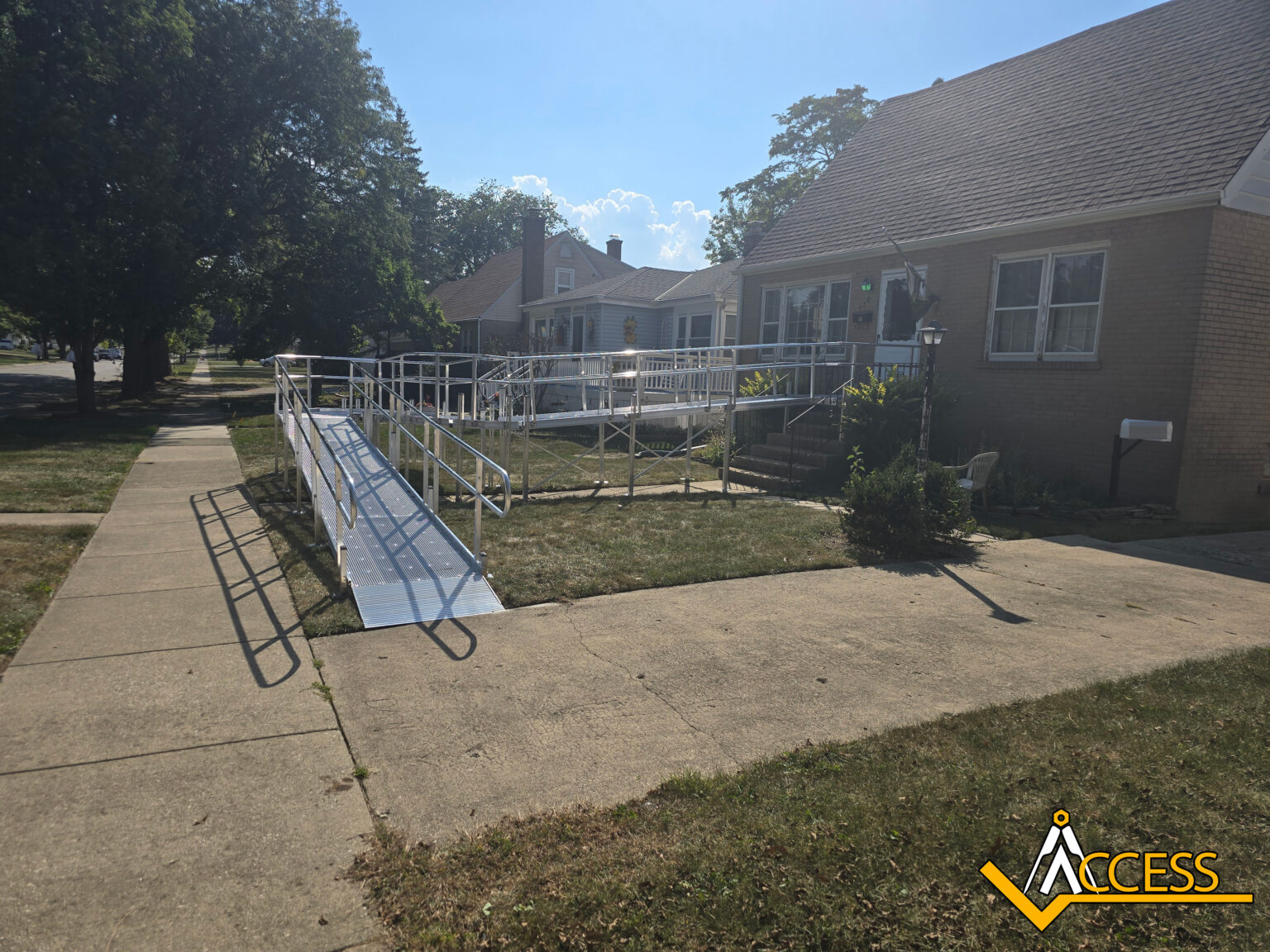 A wheelchair-accessible ramp made of metal extends from the sidewalk to ...