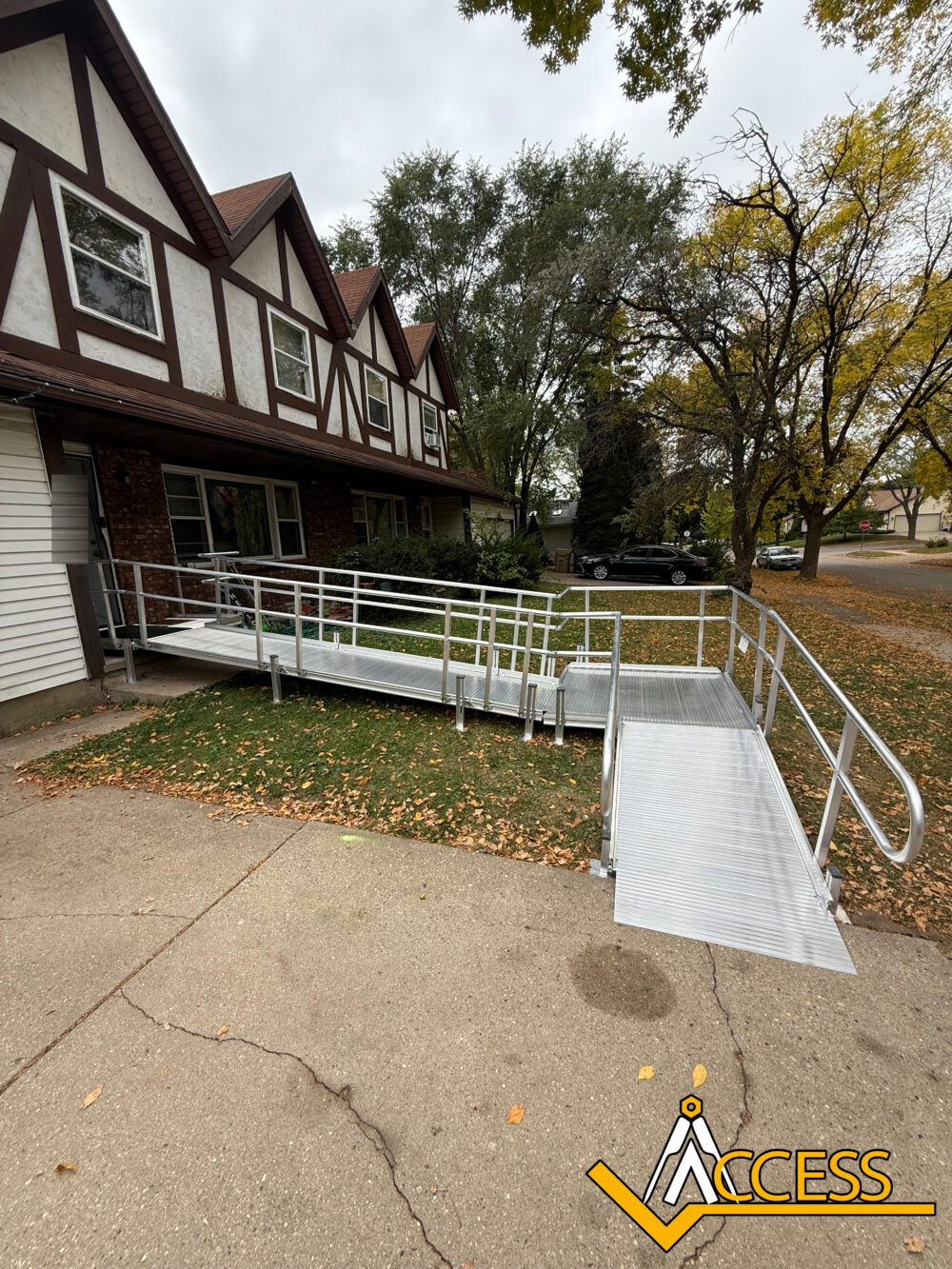 An aluminum wheelchair ramp with railings leads from a sidewalk to the ...