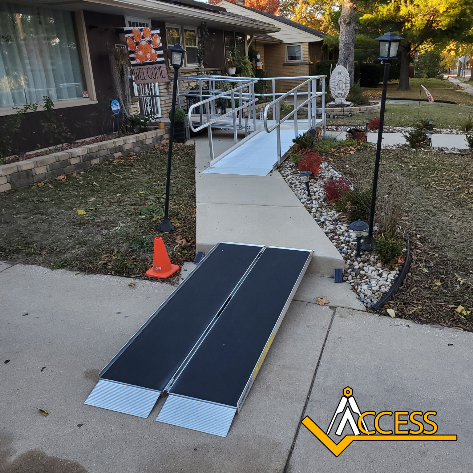 A concrete walkway leads to a metal wheelchair ramp attached to a house ...