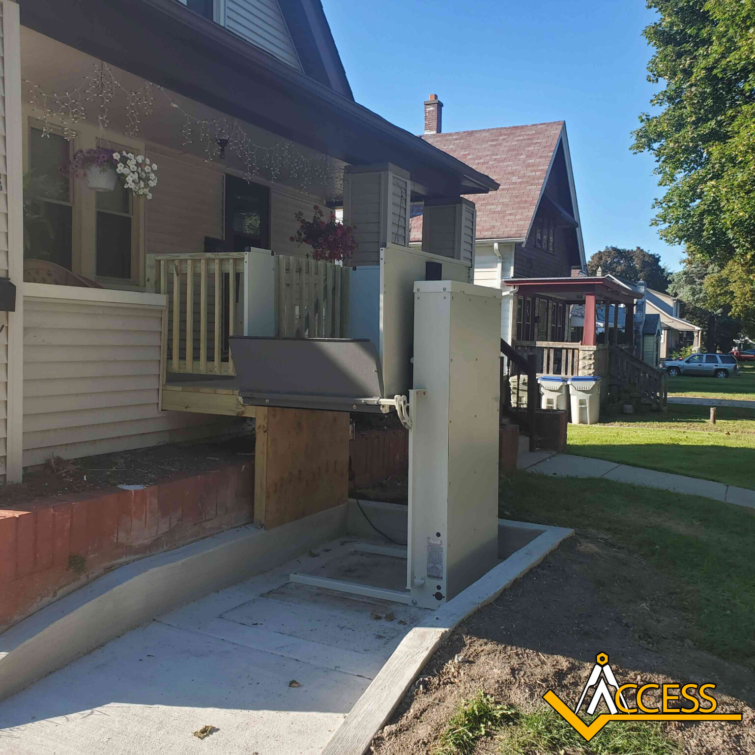 A wheelchair lift is installed at the front steps of a house, providing ...
