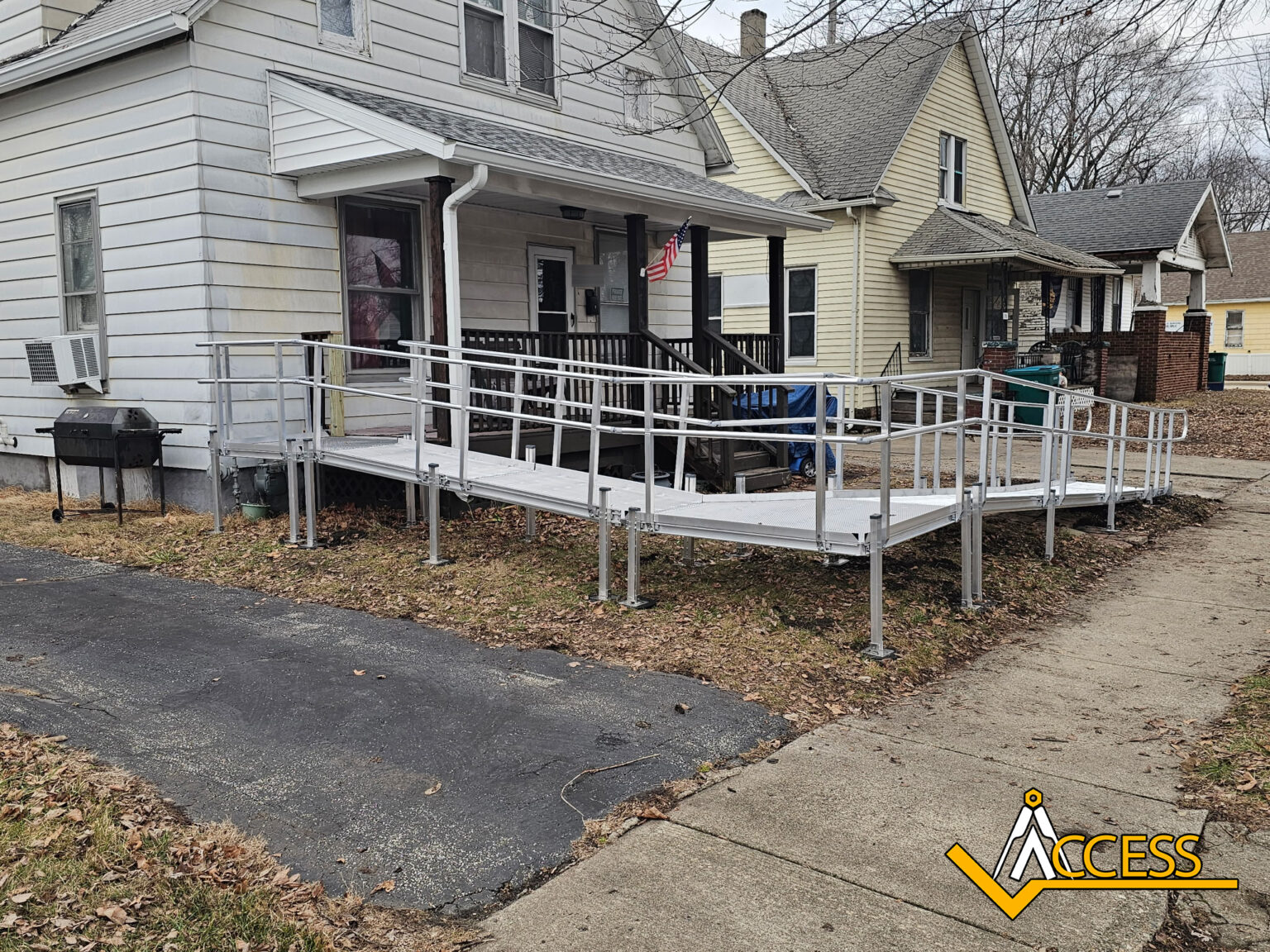 A metal wheelchair ramp with railings leads from the sidewalk to the ...