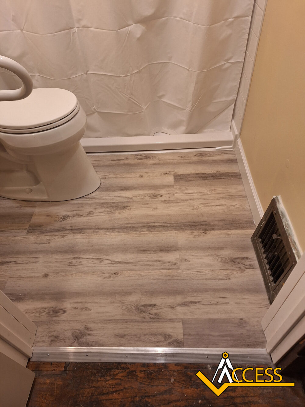 A small bathroom with a white toilet, wood-look vinyl flooring, white ...
