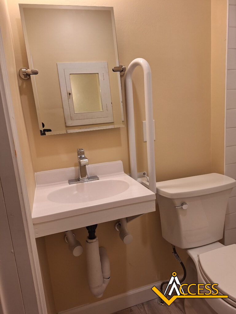 Small accessible bathroom with a wall-mounted sink, exposed plumbing ...