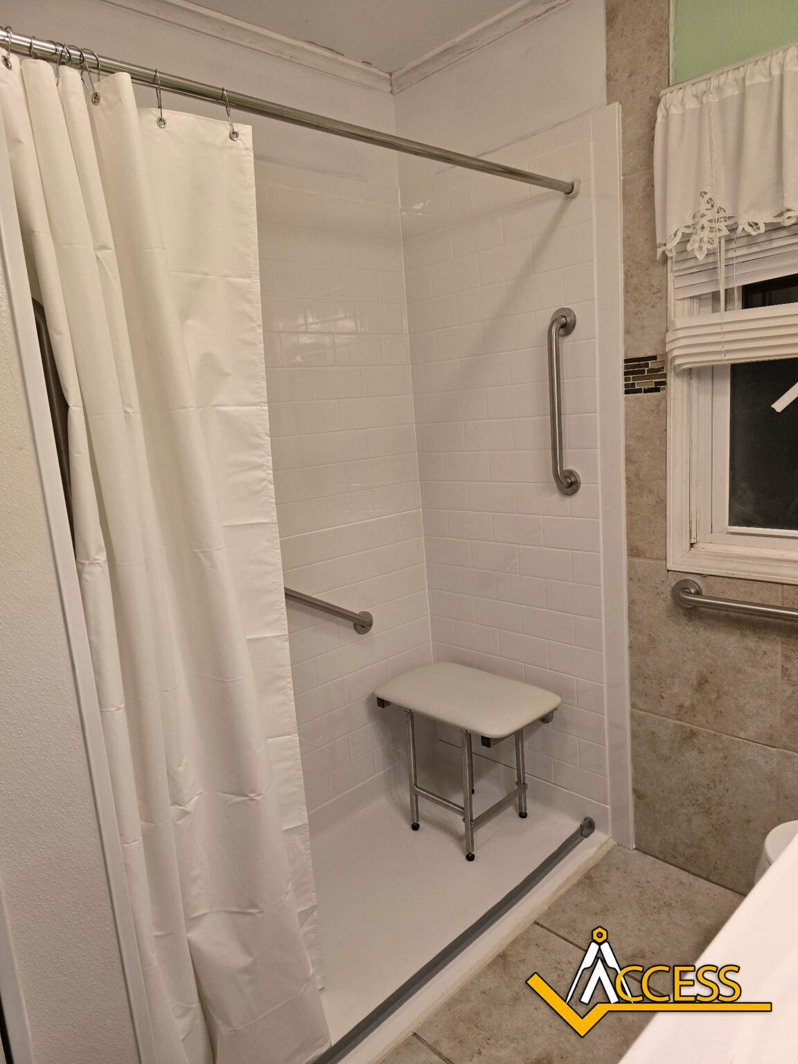 Accessible shower with a white curtain, grab bars on two walls, a ...
